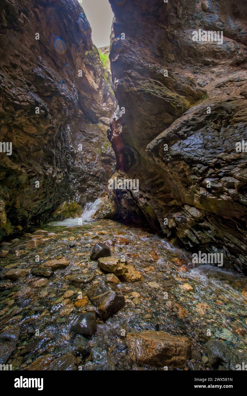 A stunning view of a narrow gorge with sunlit rocky walls, with a ...