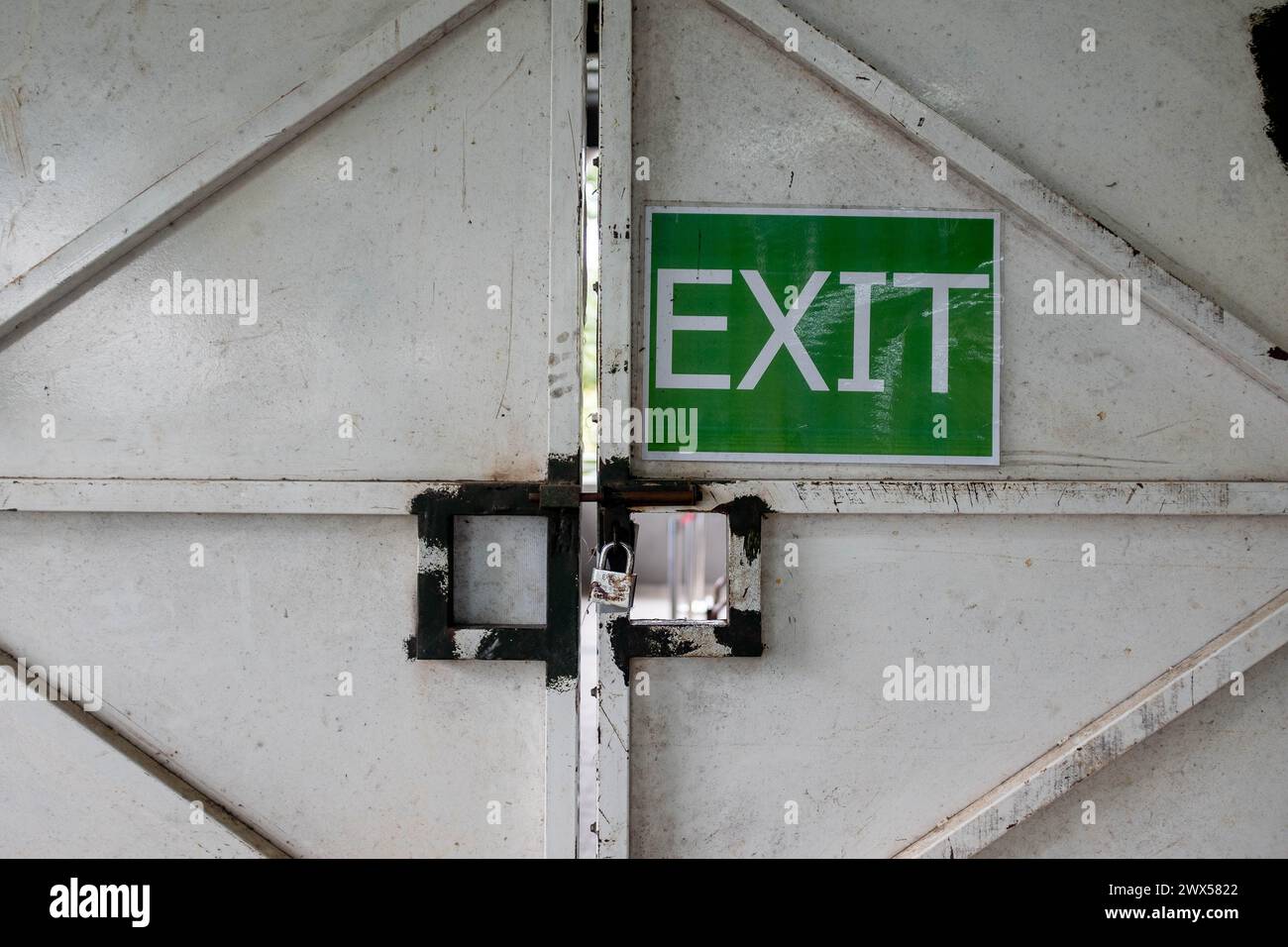 A white painted metal gate used for entrance and exit with EXIT sign in ...