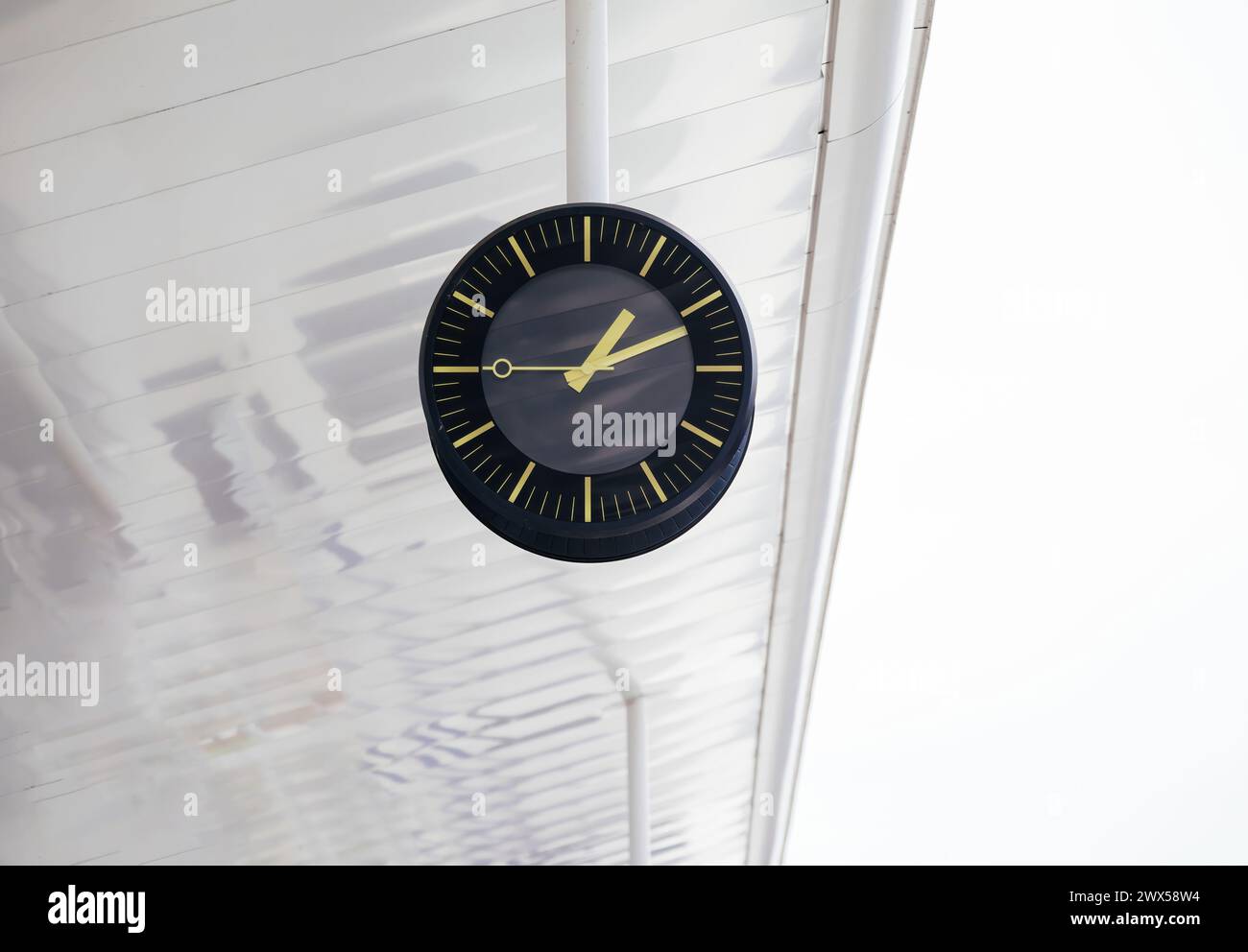 A clock is suspended from the ceiling of a building, ticking away the ...