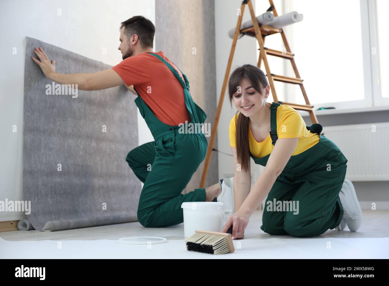 Workers hanging stylish gray wallpaper in room Stock Photo - Alamy