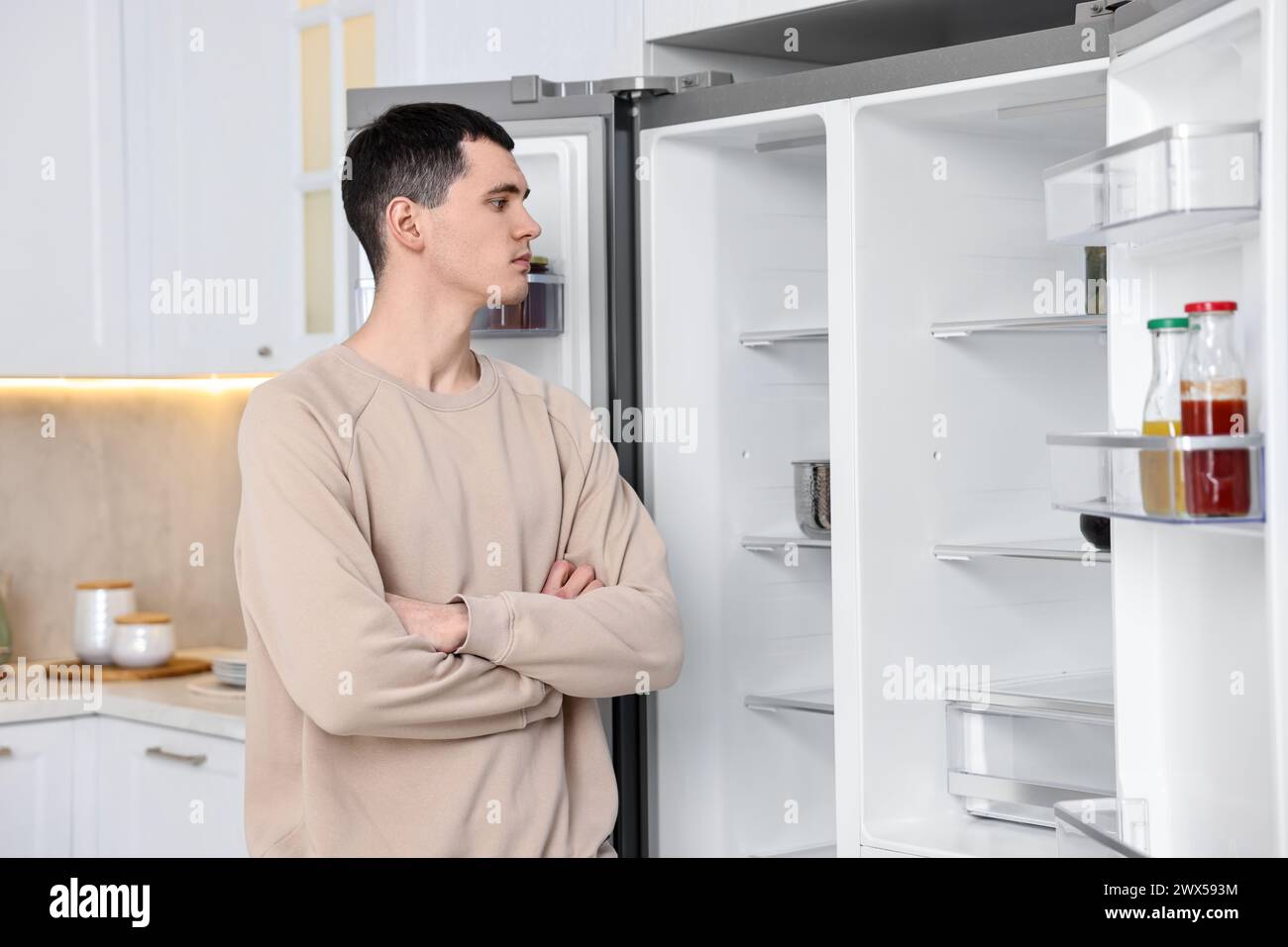 Upset man near empty refrigerator in kitchen Stock Photo - Alamy