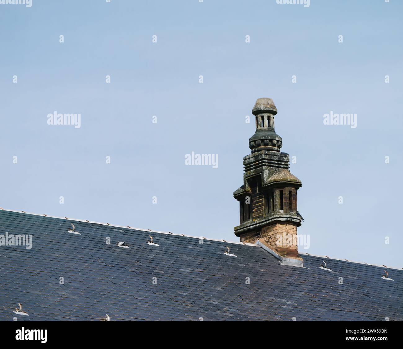 A close-up captures the intricate details of a stone chimney atop a ...