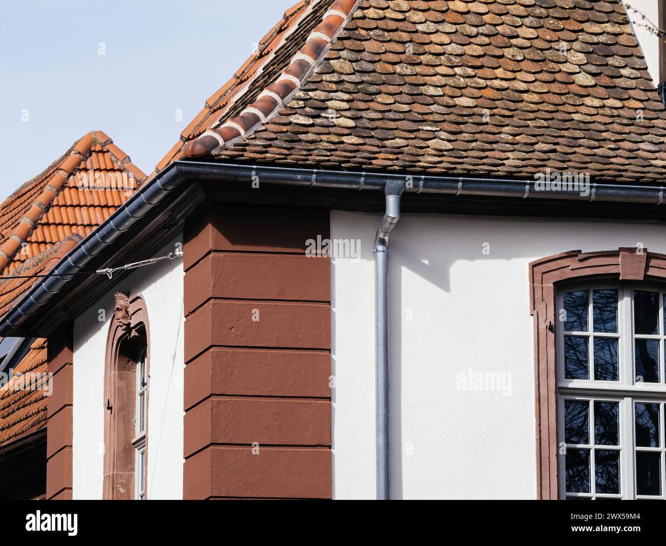 A house with brown and white walls and a distinctive red roof stands ...