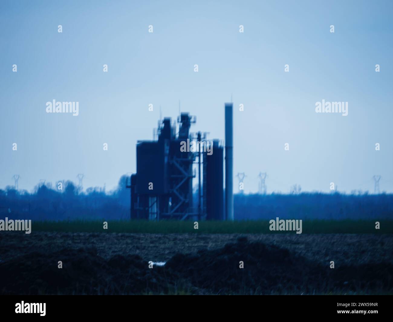 A factory with smoke billowing out of its stacks, depicting industrial ...