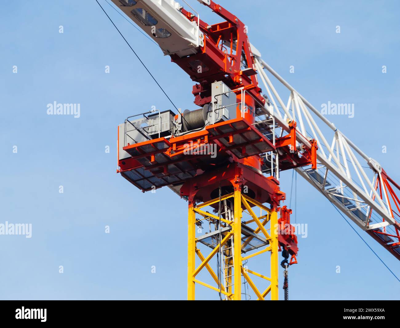 A red and white crane soars gracefully against a clear blue sky ...