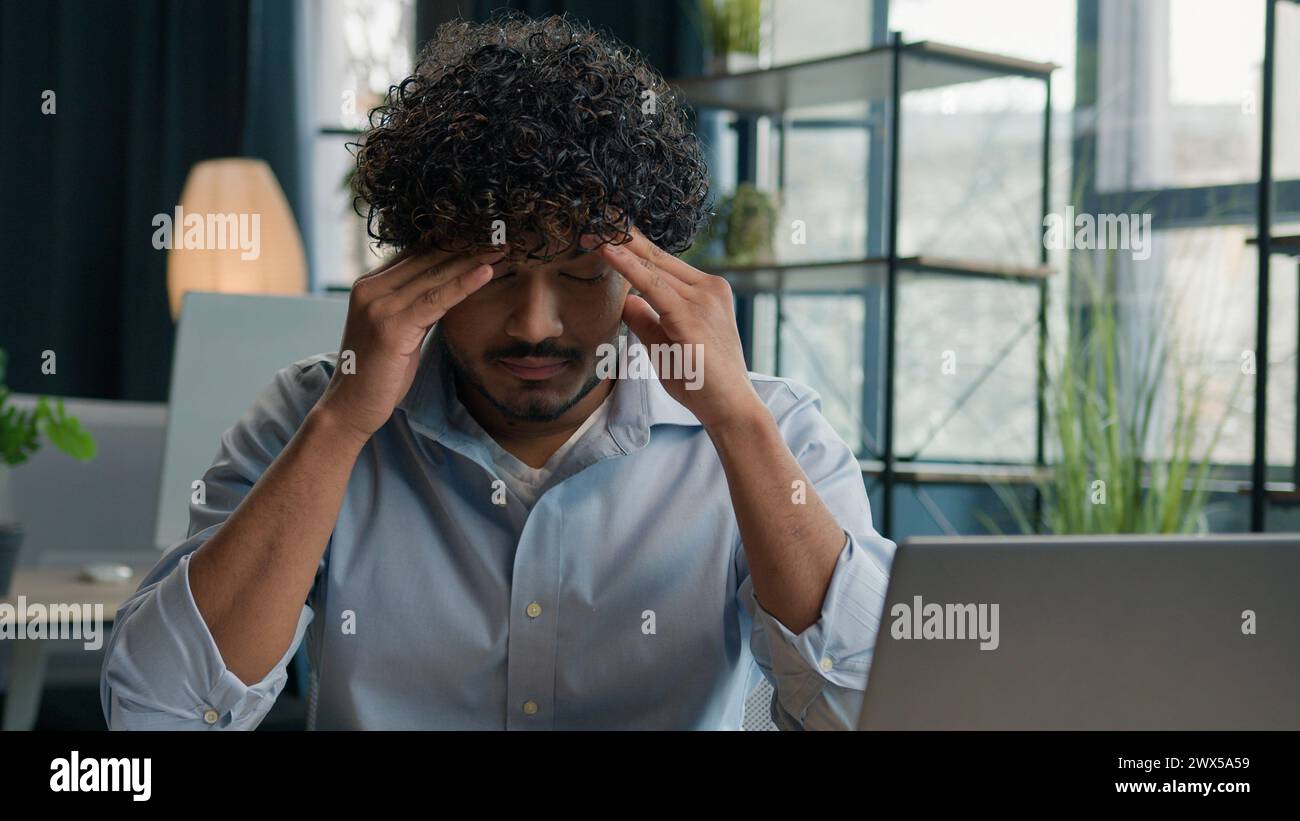 Tired overworked Indian Arabian man businessman working with laptop ...