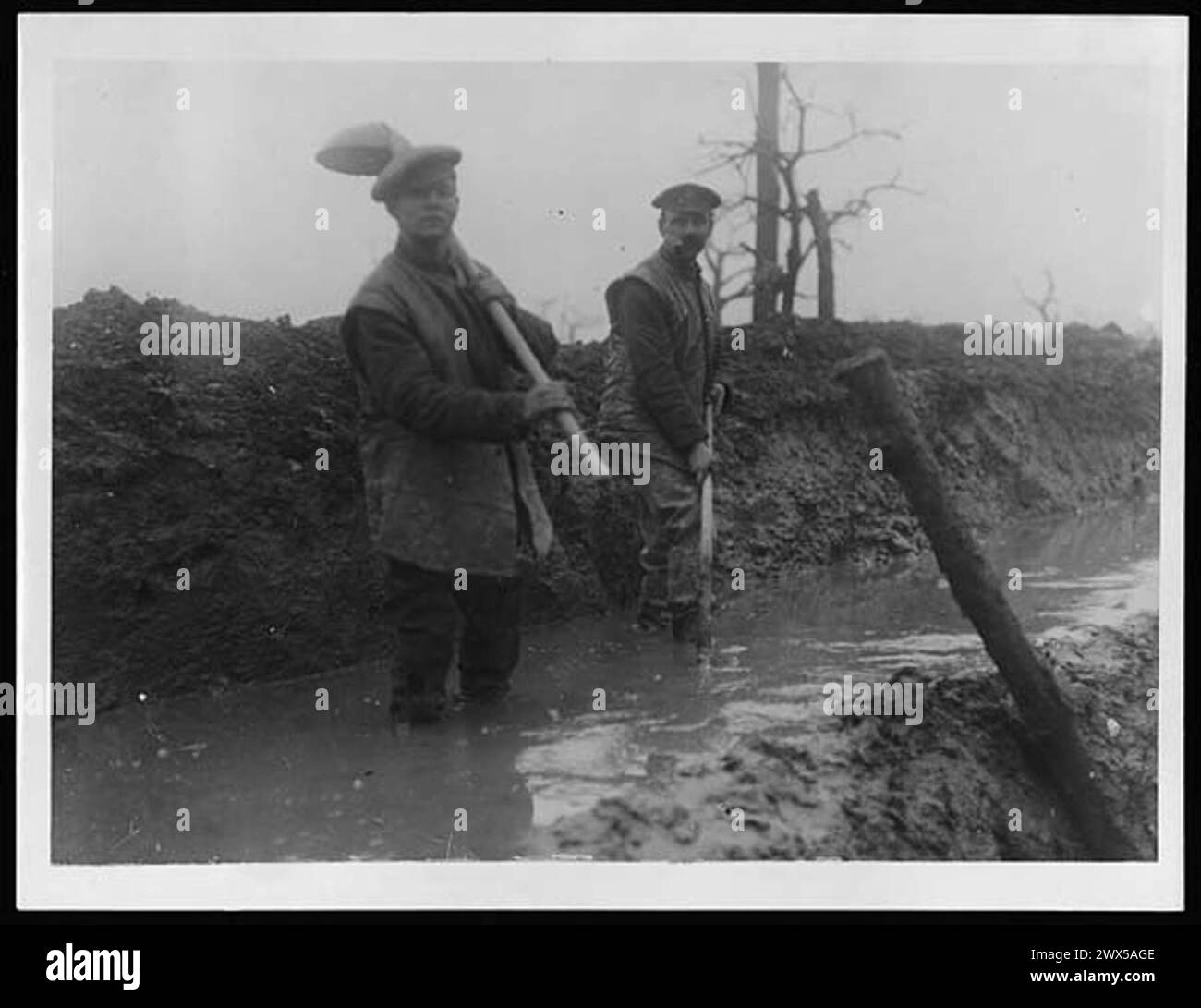 Two soldiers standing knee deep in liquid mud in a trench on the Somme ...