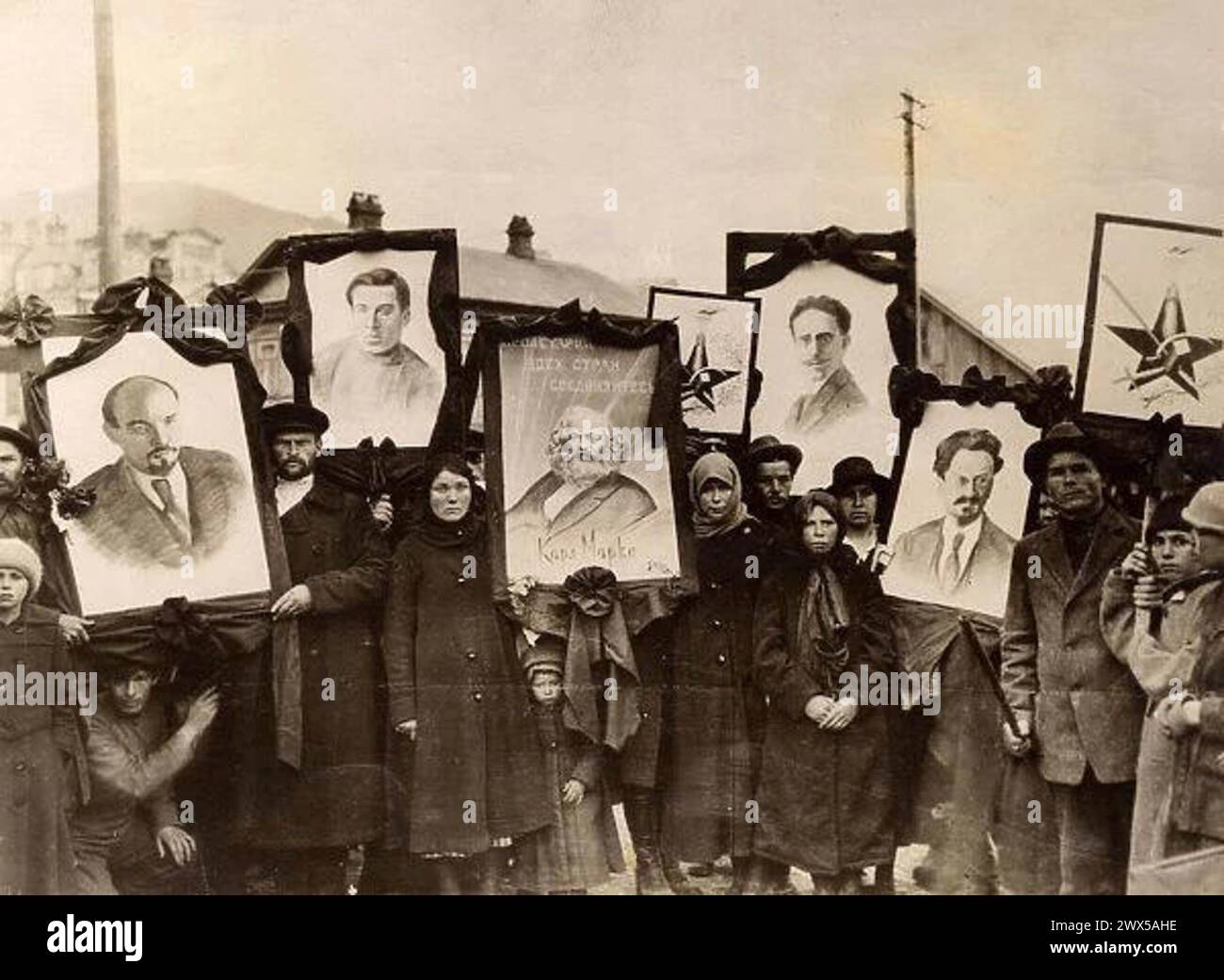 Russian peasants holding banners of Lenin (left), Marx (centre) and ...