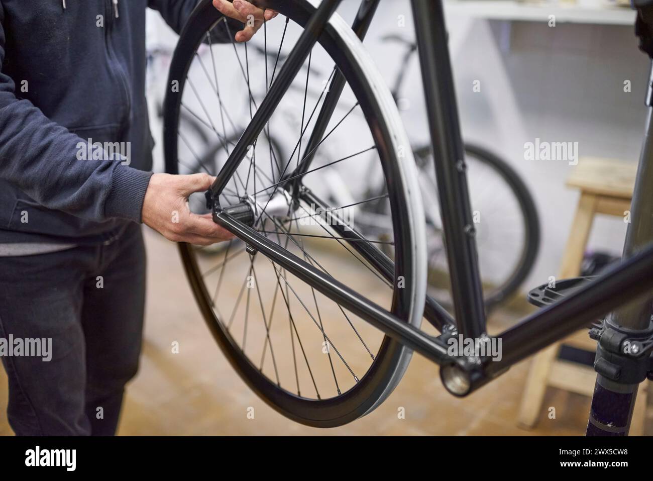 Unrecognizable man putting on the rear wheel of a bicycle he is ...