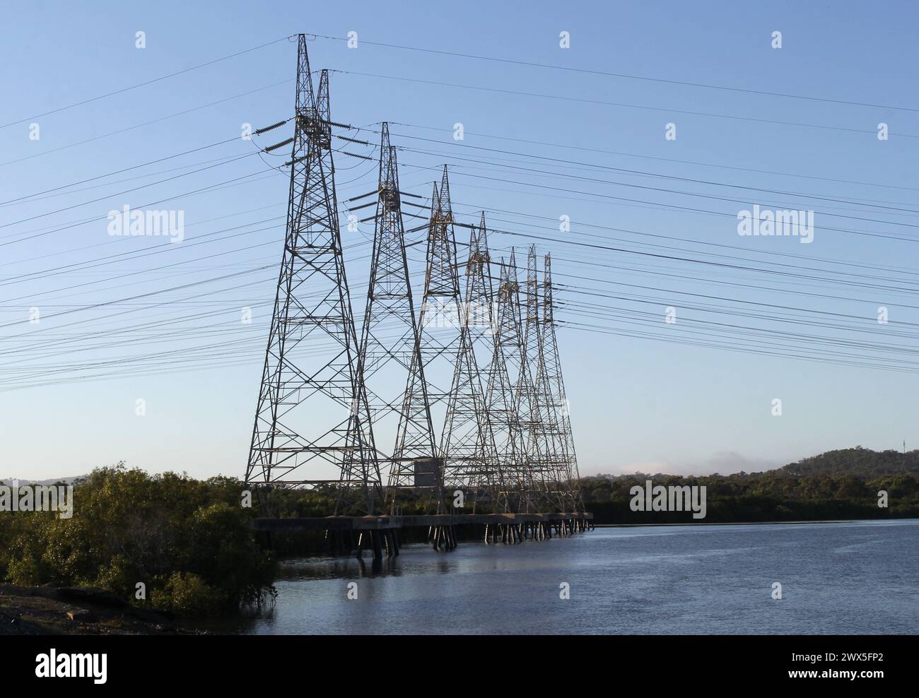 Electricity towers with power lines next to a river of water Stock ...
