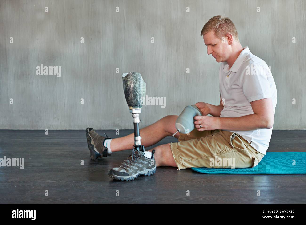 Man, amputee and prosthetic leg in gym sitting to attach, residual limb ...