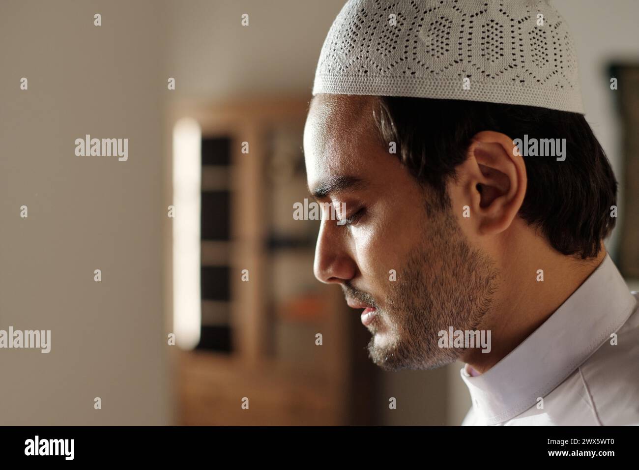 Side view closeup of young Muslim man wearing white taqiyah on head ...