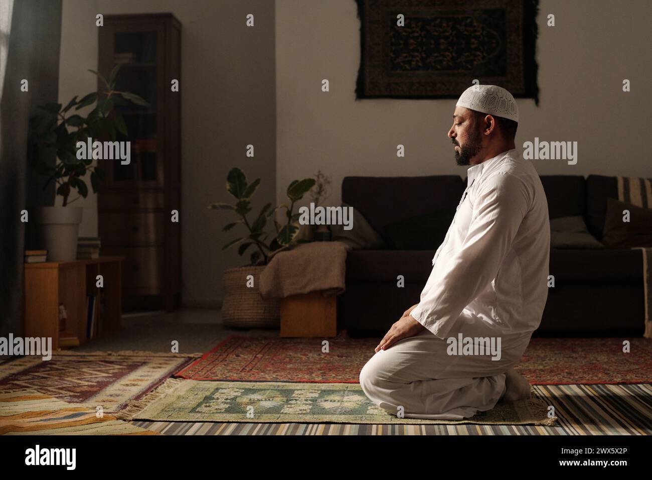 Side view shot of mature Muslim man wearing white clothes sitting on ...