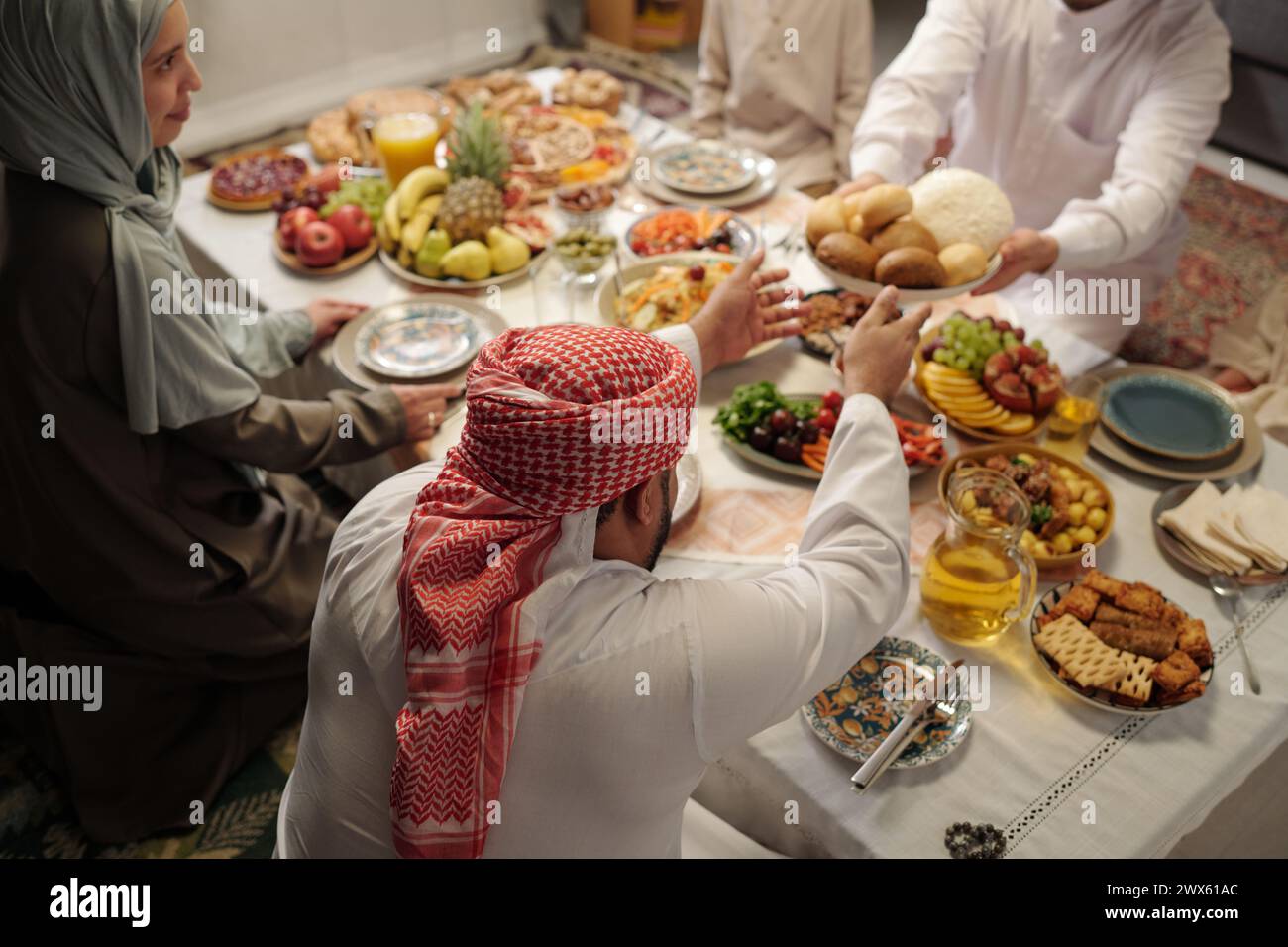 High angle view of young Muslim man sharing food with his family at ...