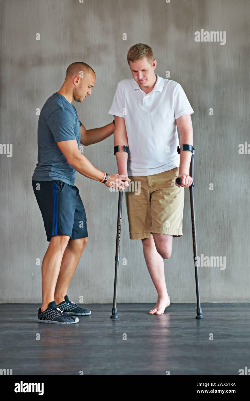 Man, amputee and crutches in physical therapy with personal trainer for ...