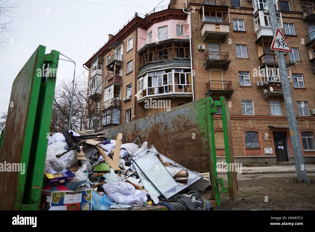 Dumpster with broken window frames in front of Ukrainian house damaged ...