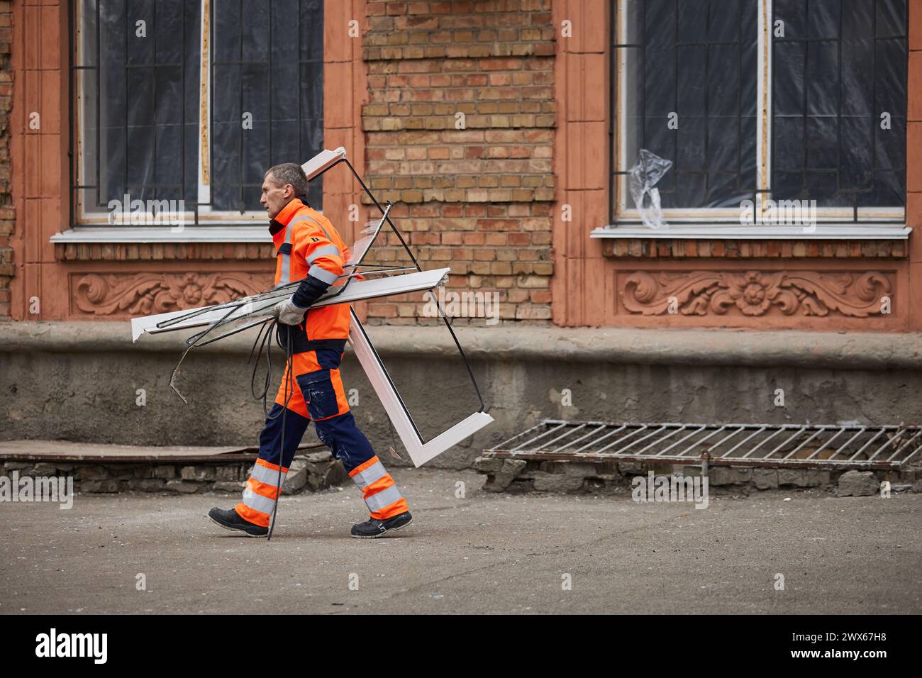 Ukrainian worker helps the clean the rubble after russian attack. Man ...
