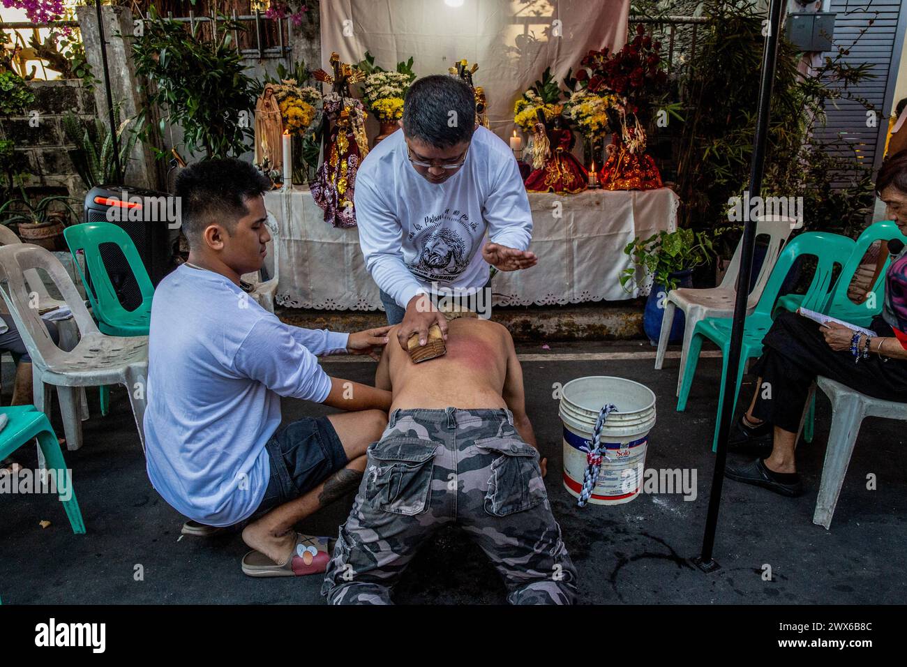 Mandaluyong City, Philippines. 28th Mar, 2024. A man wounds the back of ...
