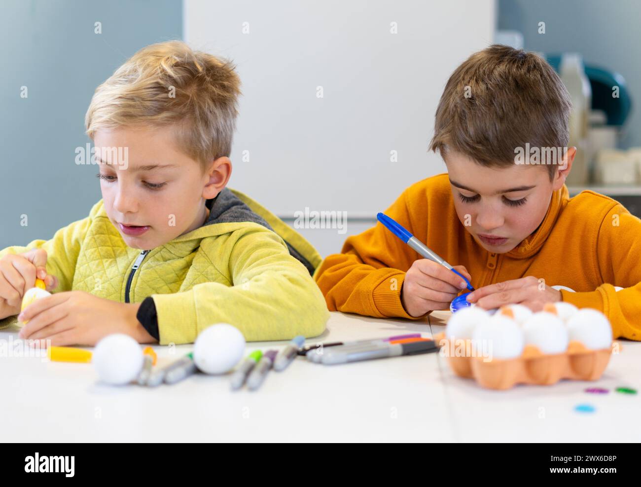 Two children putting colored Easter eggs to decorate Stock Photo - Alamy