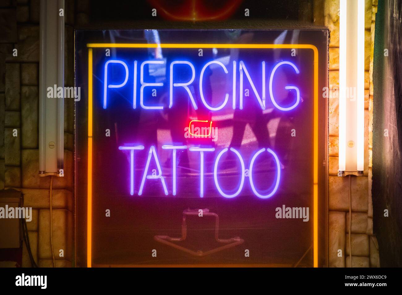 Neon sign piercing and tattoo on display at Camden market in London, UK ...
