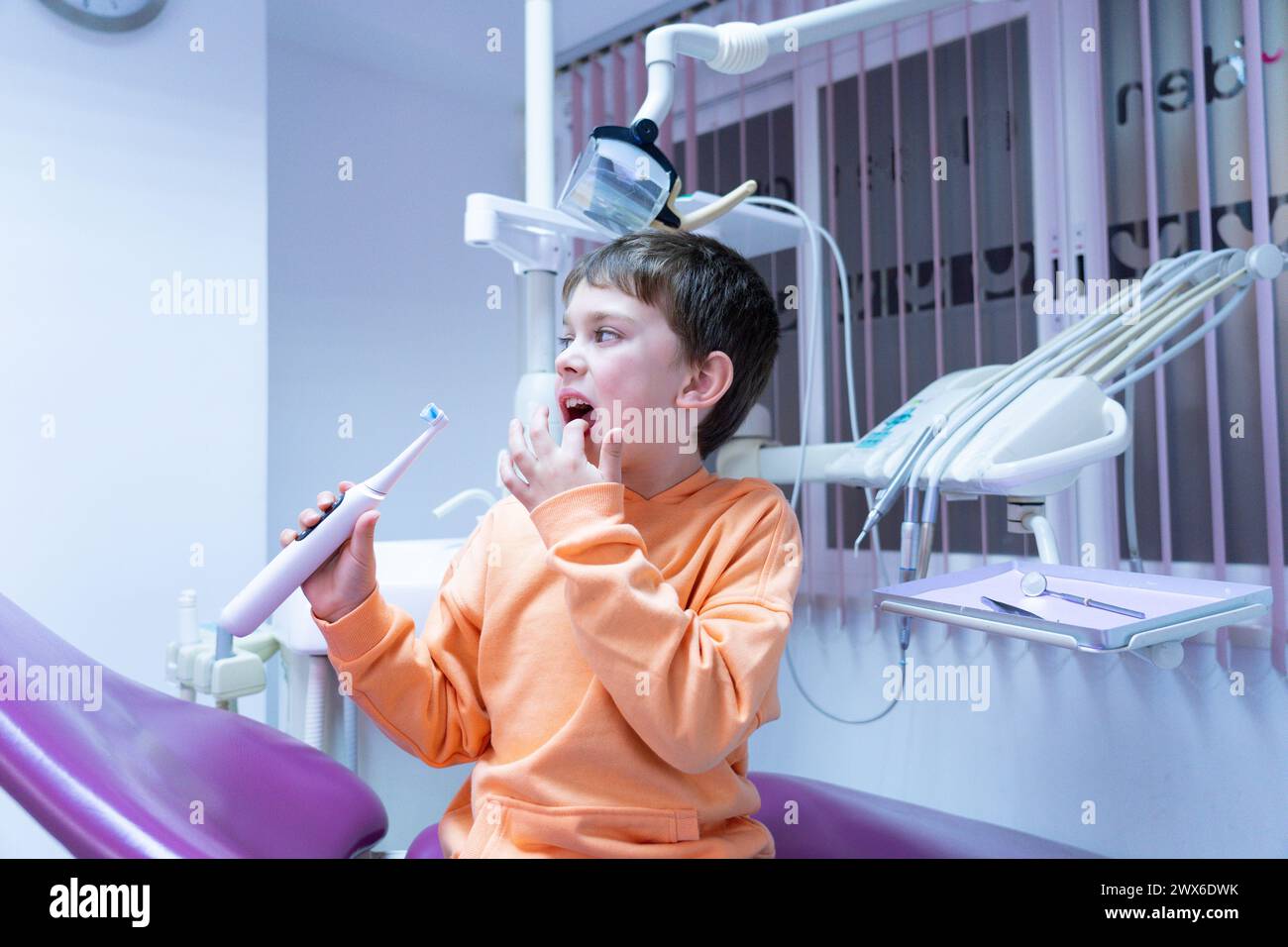 Boy in a dentist's chair with an electric toothbrush Stock Photo - Alamy