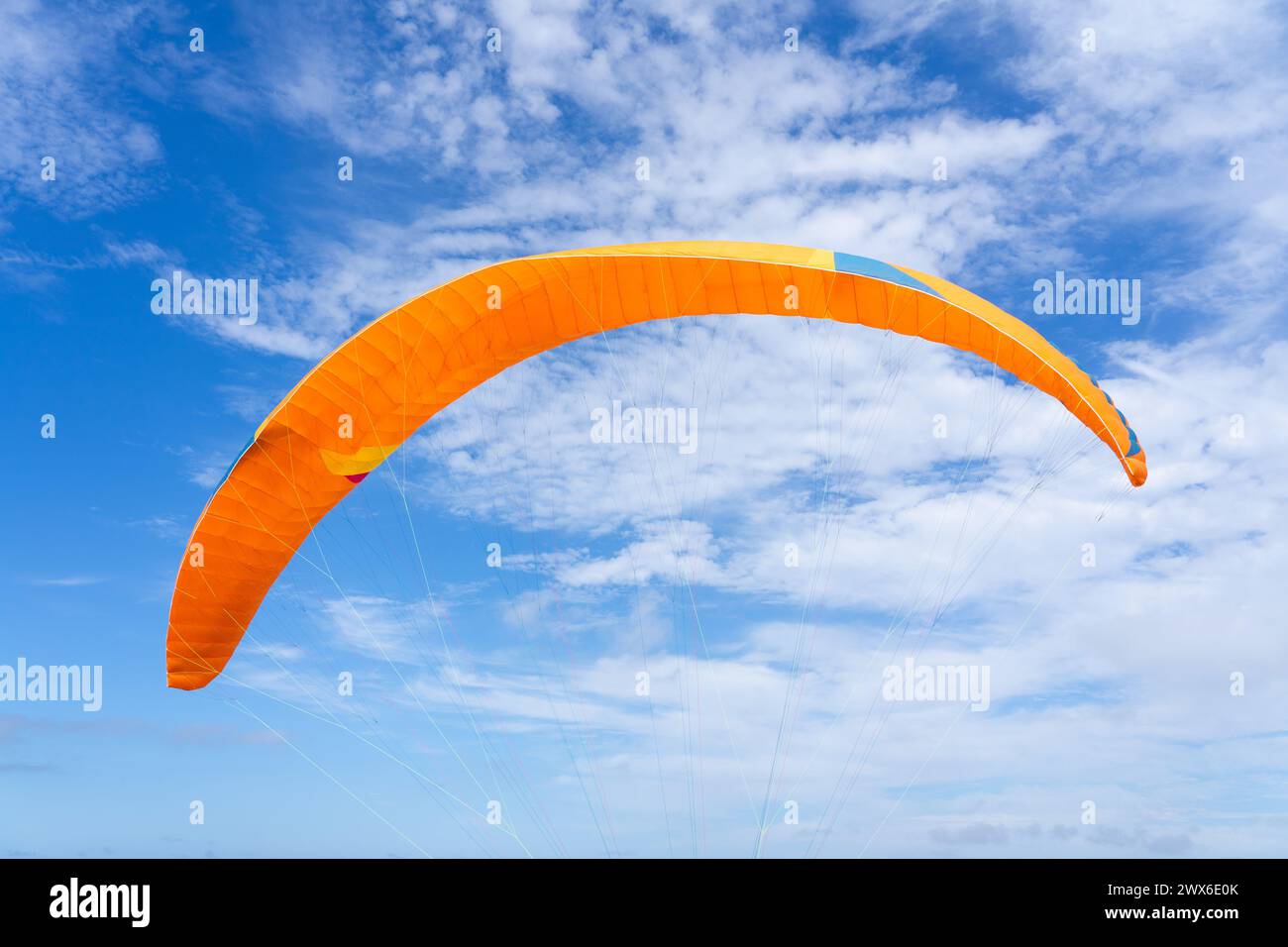 Orange paragliding sail with a blue sky background with copy space ...