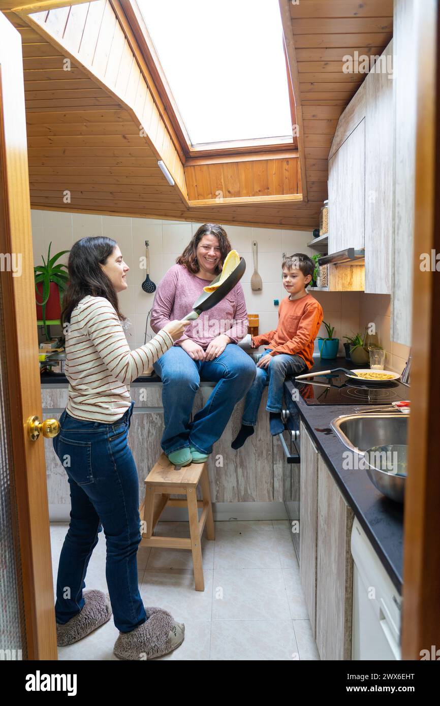 LGBT family cooking pancakes at home, flipping the pancake in the pan ...