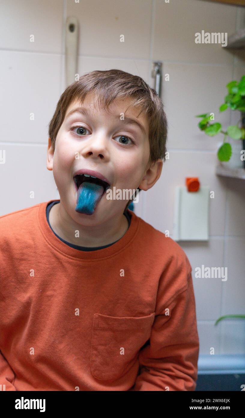Boy showing his blue tongue for a candy Stock Photo - Alamy