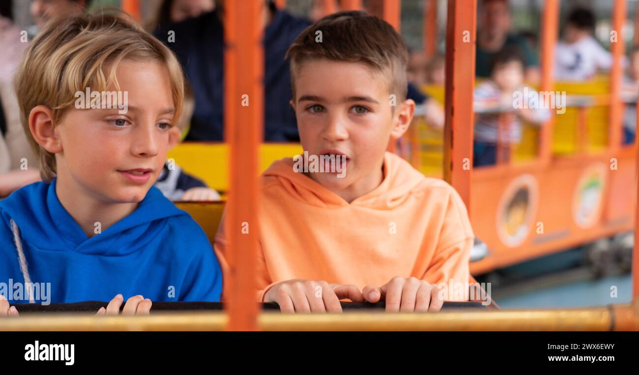 Two Caucasian children riding a train ride at an amusement park Stock ...