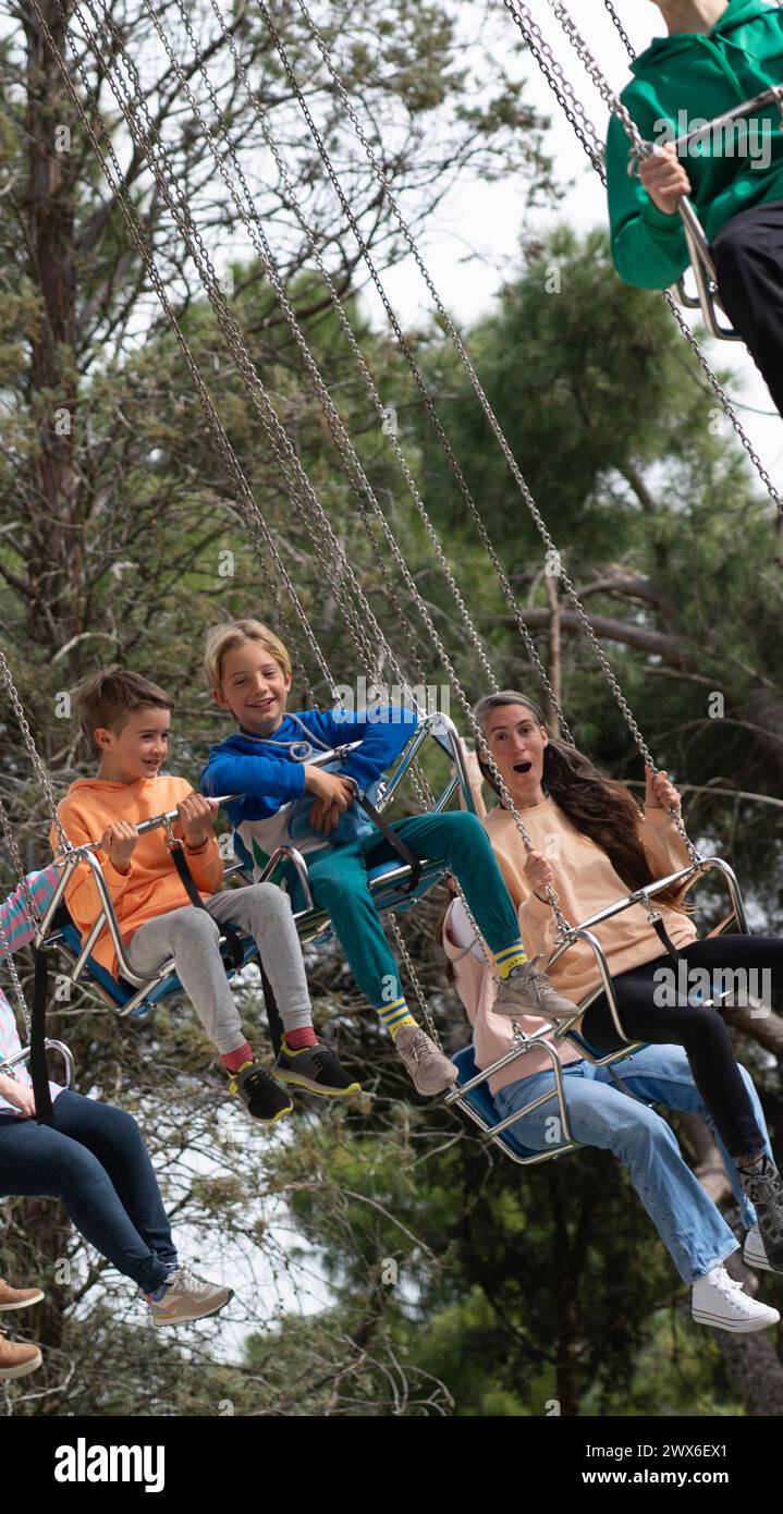 Family of a mother and two children riding on a flying swing attraction ...