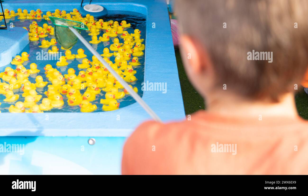 Boy playing a fairground game of catching rubber ducks Stock Photo - Alamy