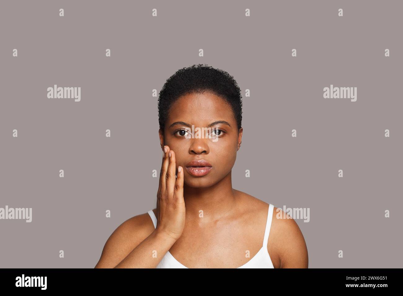 Shocked serious model woman with dark shiny skin and cute smile close ...