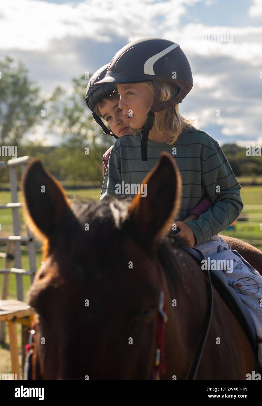 Two children riding horses together on a ranch Stock Photo - Alamy
