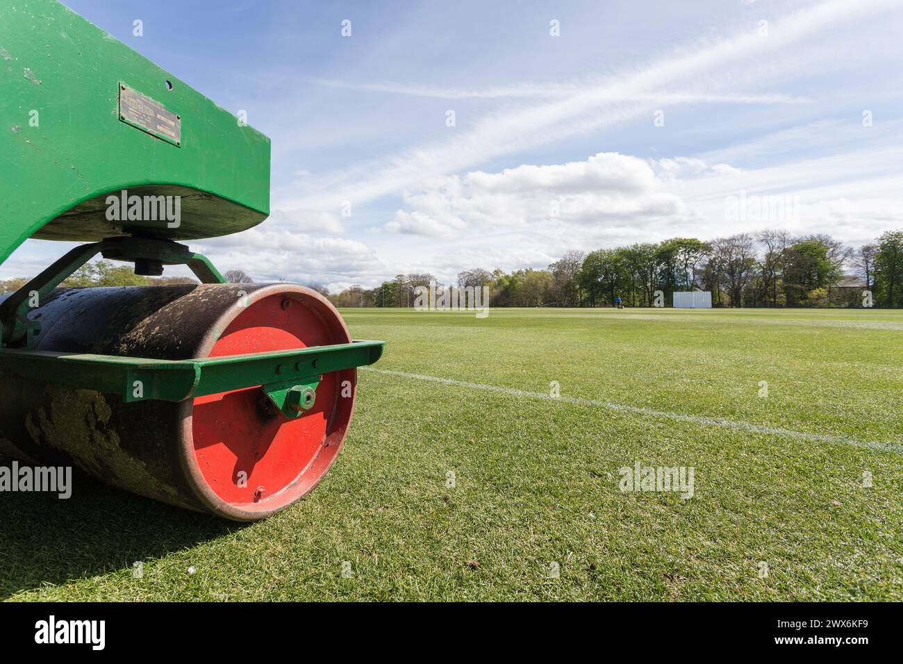 Low down image of a cricket pitch roller in the foreground with the ...