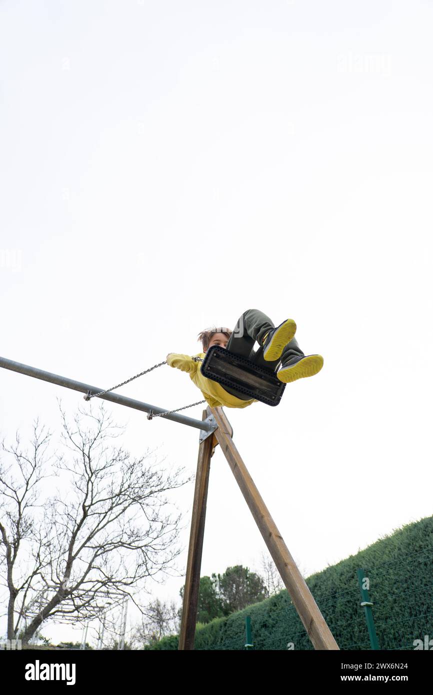 Boy on a swing swinging high seen from below Stock Photo - Alamy