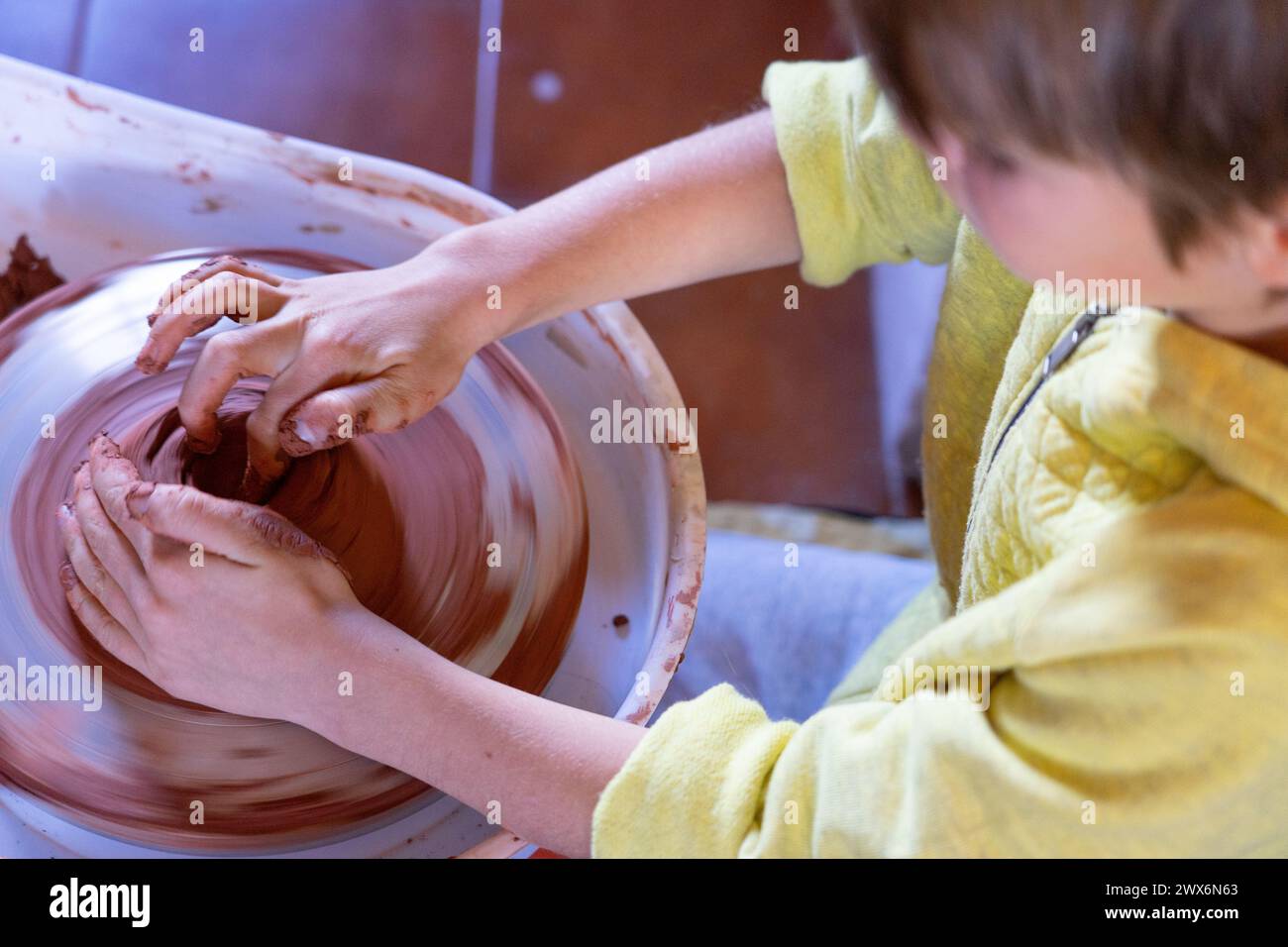 Boy learning to make pottery in a wheel class Stock Photo - Alamy