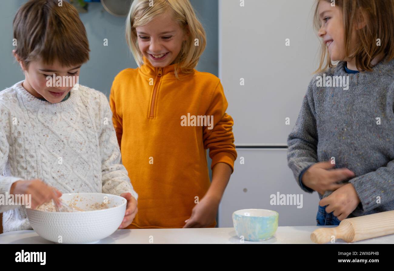 Three happy children cooking at home together Stock Photo - Alamy