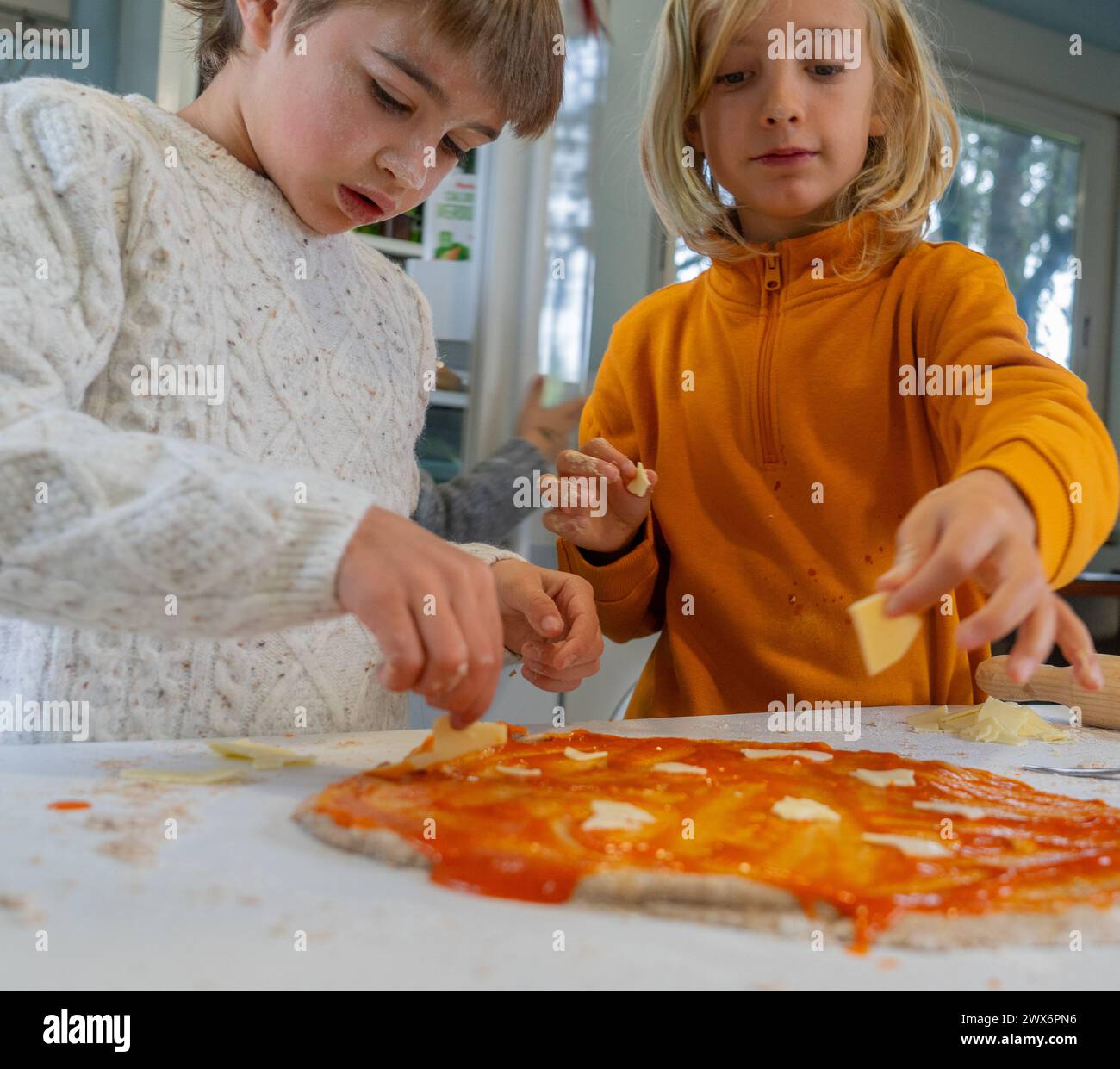 Two brothers adding ingredients to a homemade pizza Stock Photo - Alamy