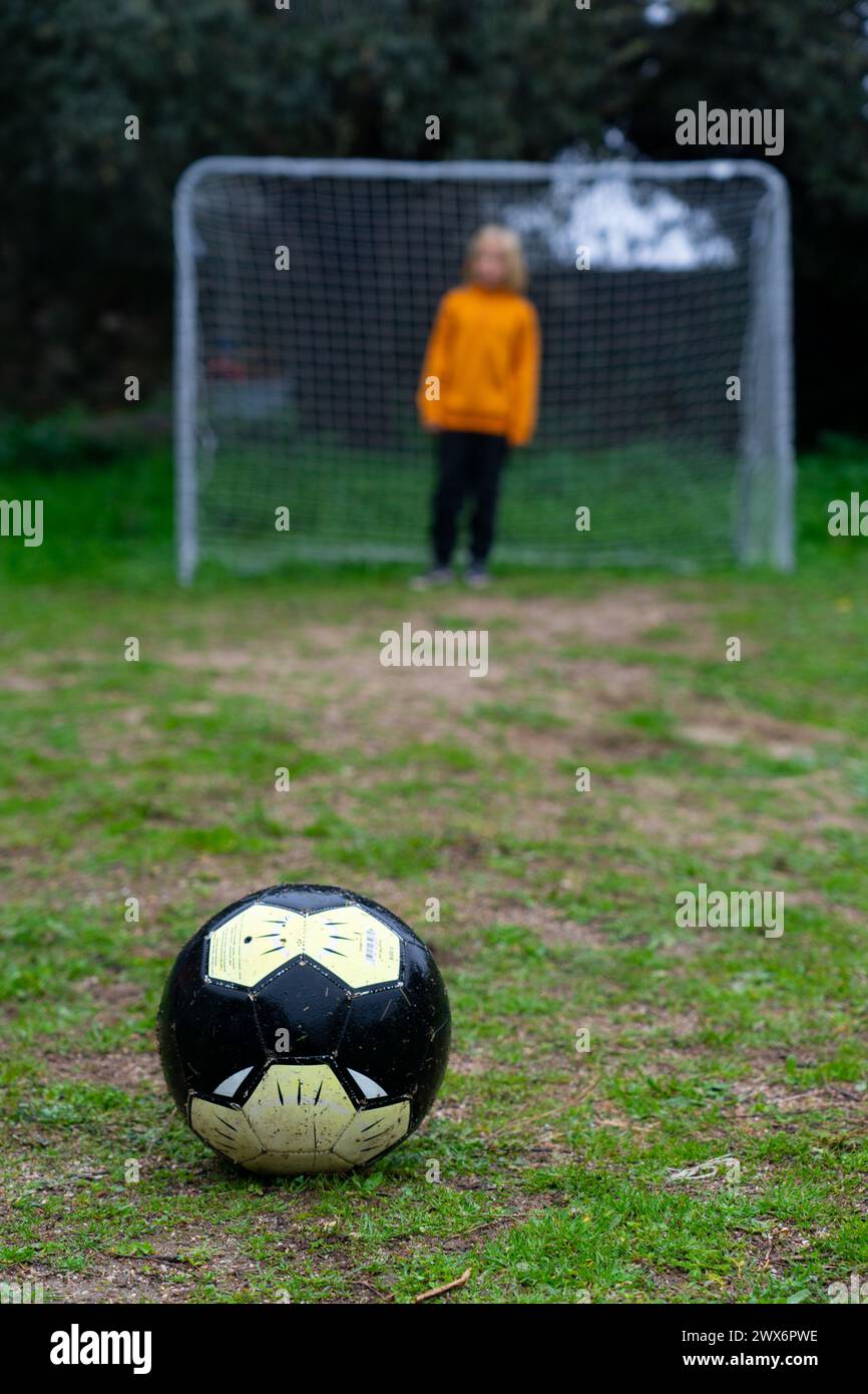Soccer ball seen up close and a child in a goal in the background Stock ...