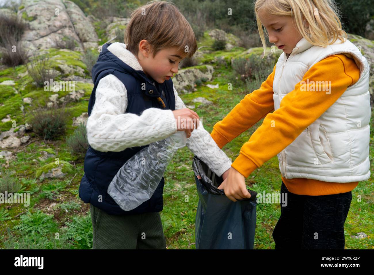 Two children collecting garbage from nature Stock Photo - Alamy