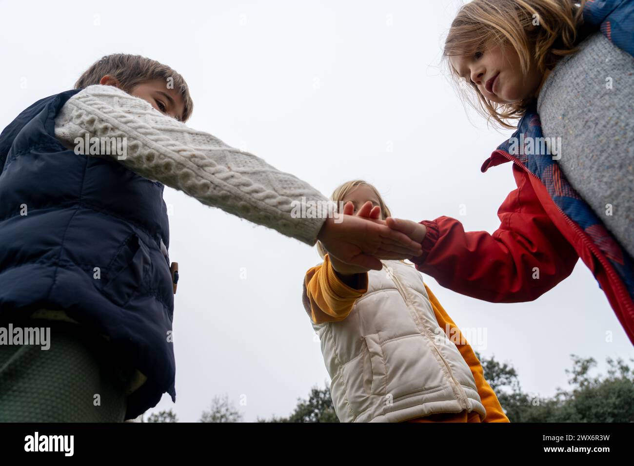 Three children putting hands on each other as a team Stock Photo - Alamy