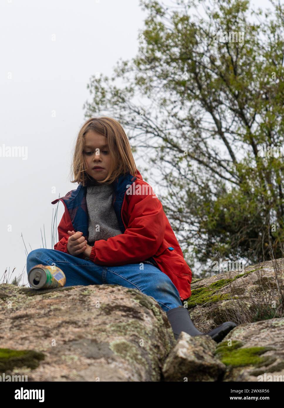 Boy in nature looking at a rusty can lying in the field Stock Photo - Alamy