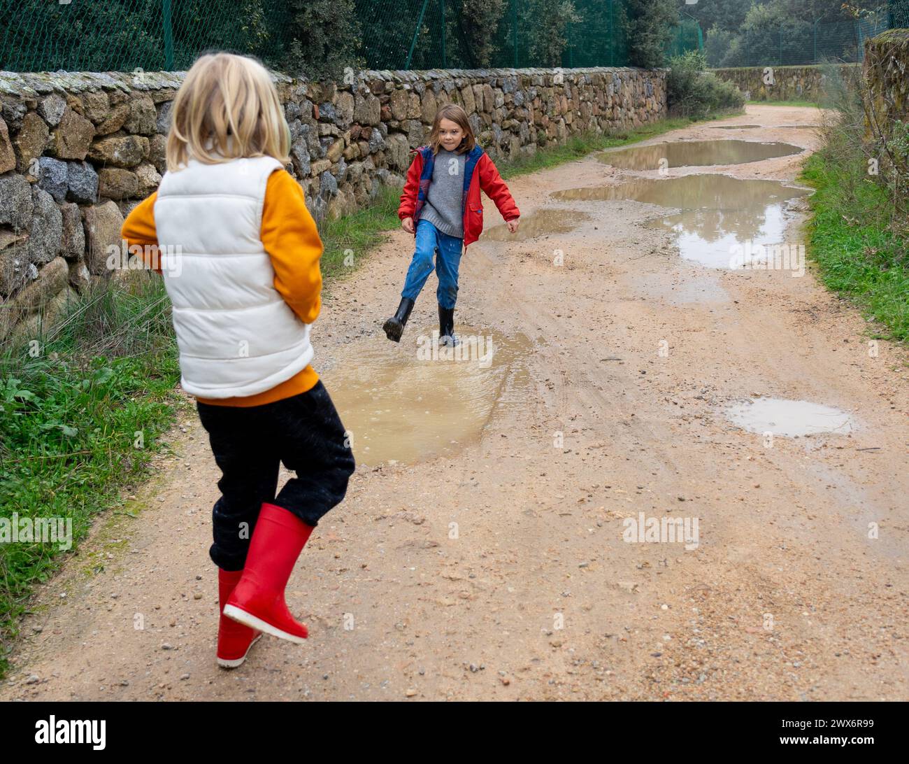 Two children playing splashing in a puddle Stock Photo - Alamy