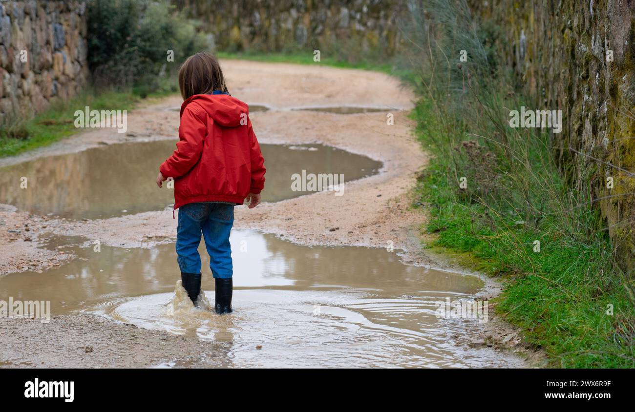 Child playing in a puddle in nature Stock Photo - Alamy