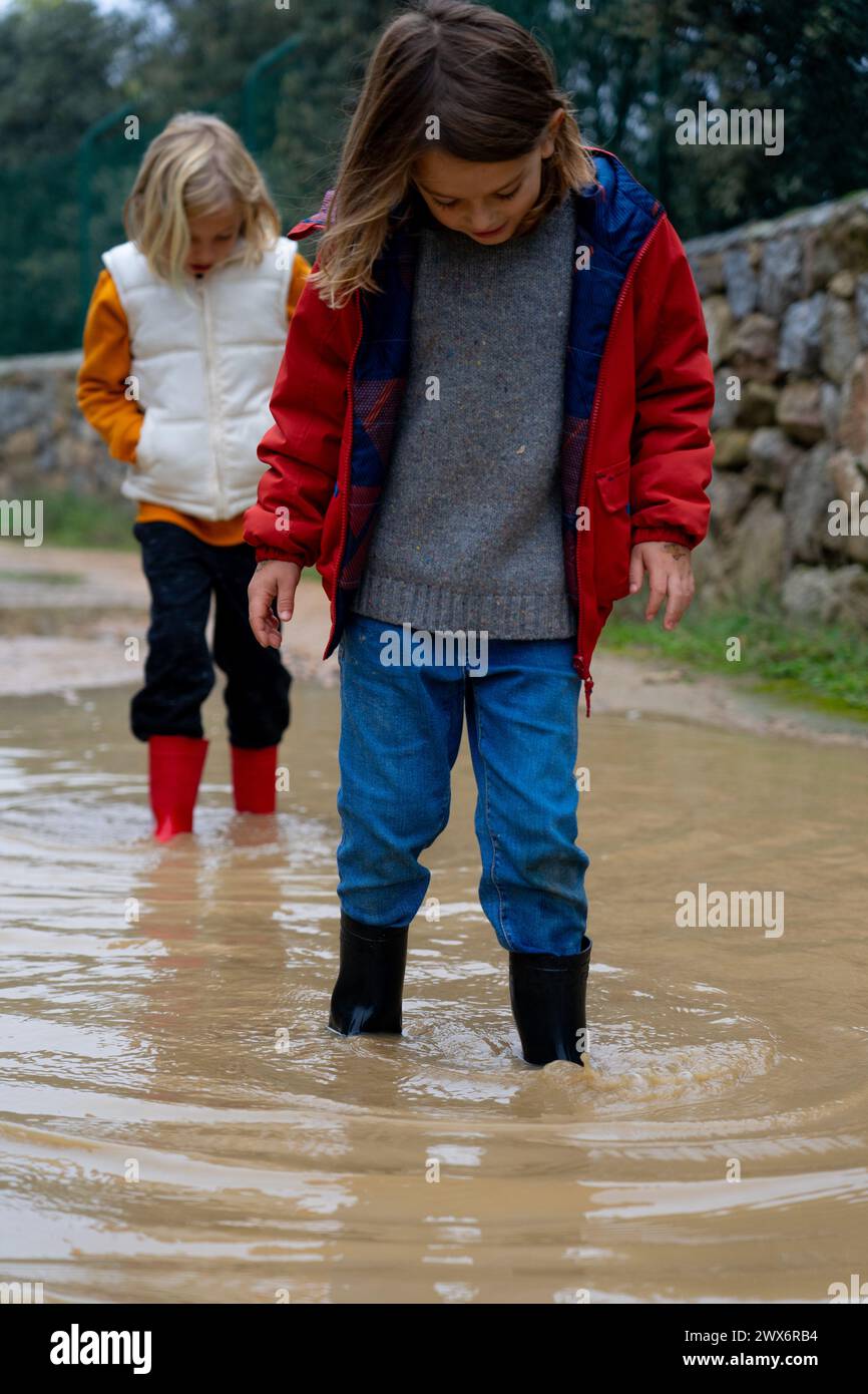 Two children playing in a puddle with wellies Stock Photo - Alamy