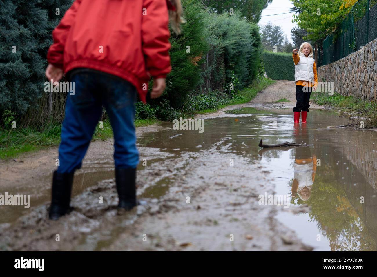Children playing outdoors in the mud of a puddle Stock Photo - Alamy