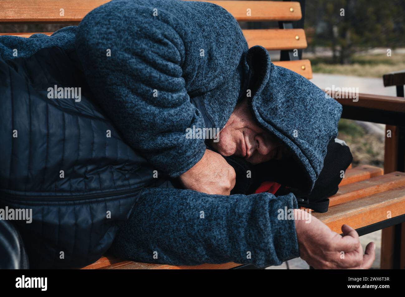 homeless elderly old Caucasian man lies sleeping on a park bench in ...