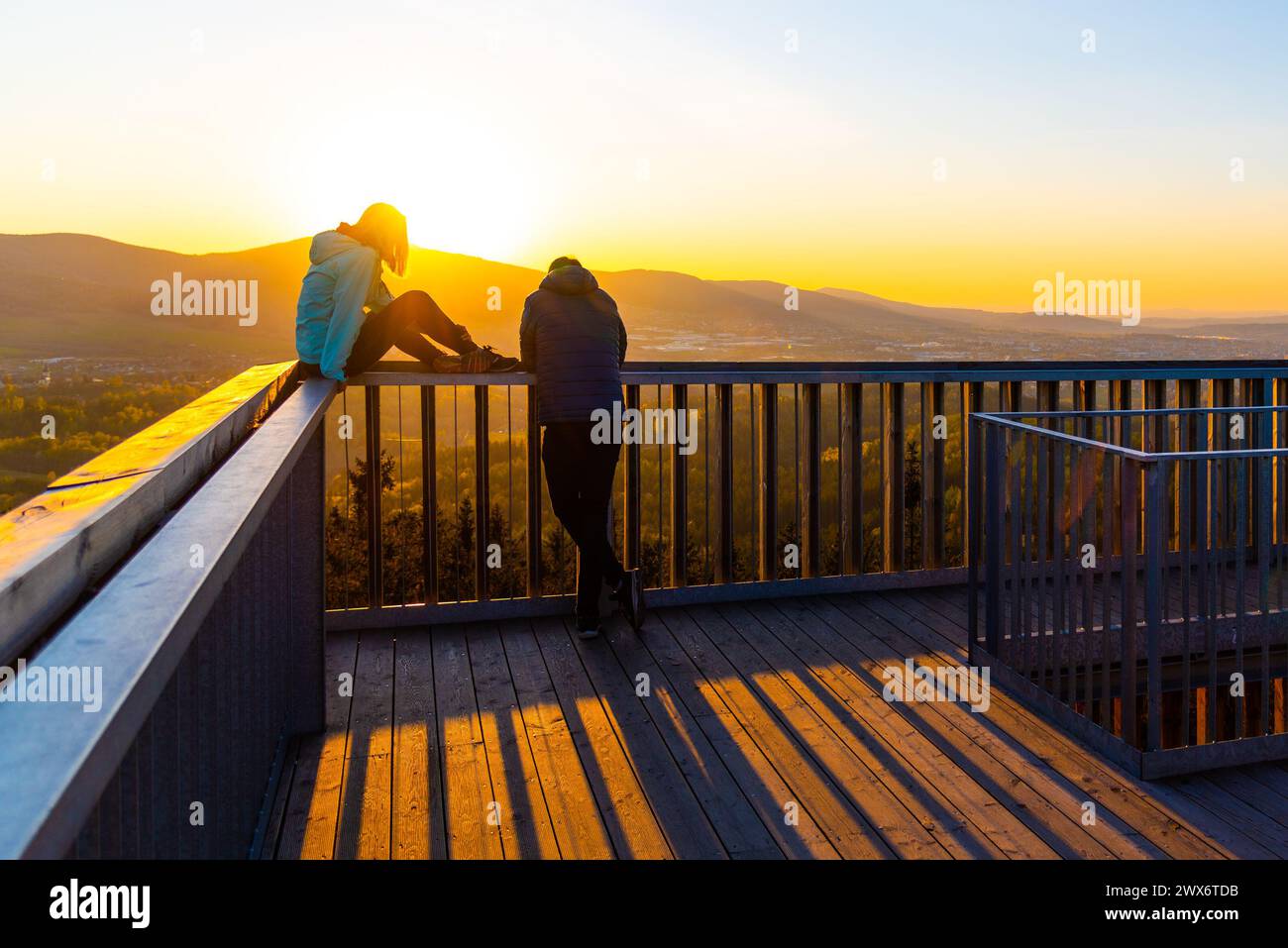 Pair enjoy a tranquil and romantic sunset from a mountain observation ...