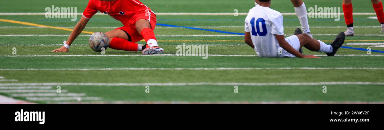 Soccer players falling while chasing a soccer ball during a game on a ...