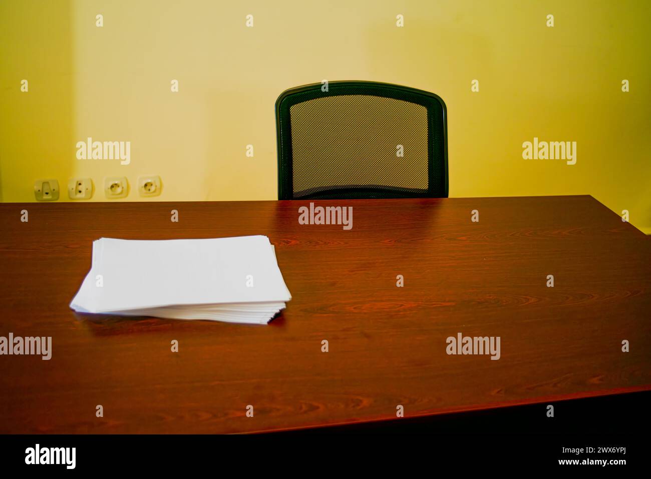 A pristine desk adorned with neatly stacked white A4 papers, creating ...